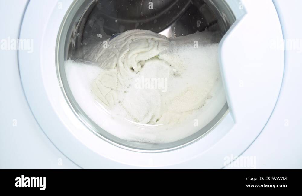 Washing machine washes white clothing and sheets. Pouring clean water ...