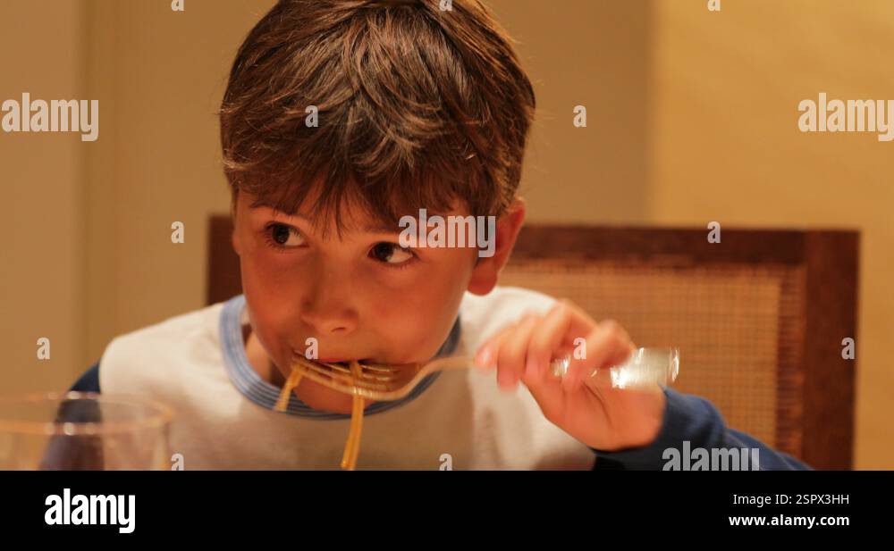 Child eating pasta for dinner. Young boy taking a bite of spaghetti ...