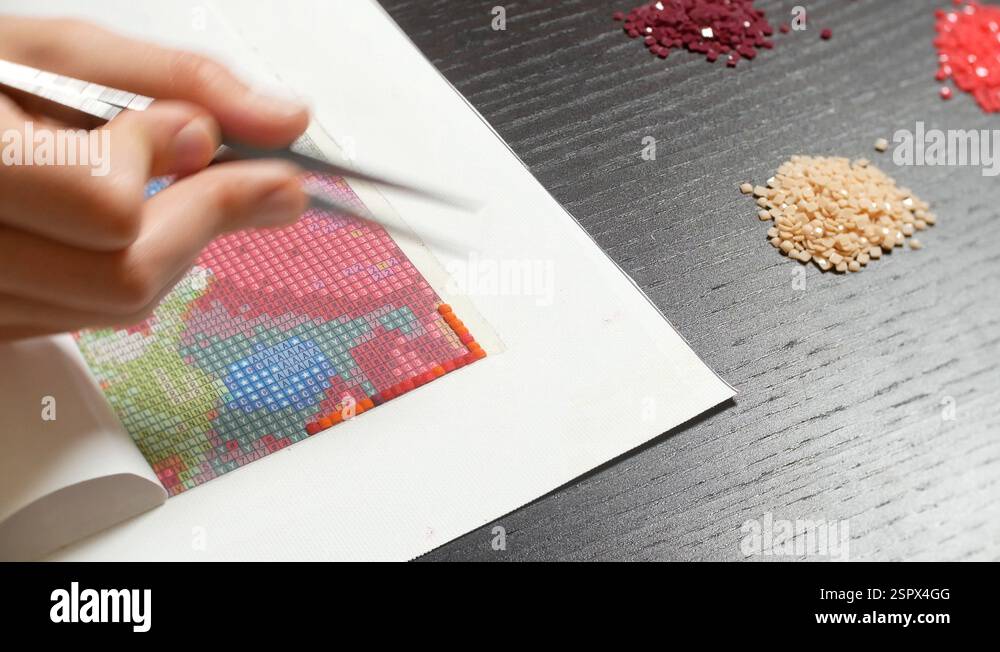 The mosaic process, the girl's hand holding tweezers, making a mosaic ...