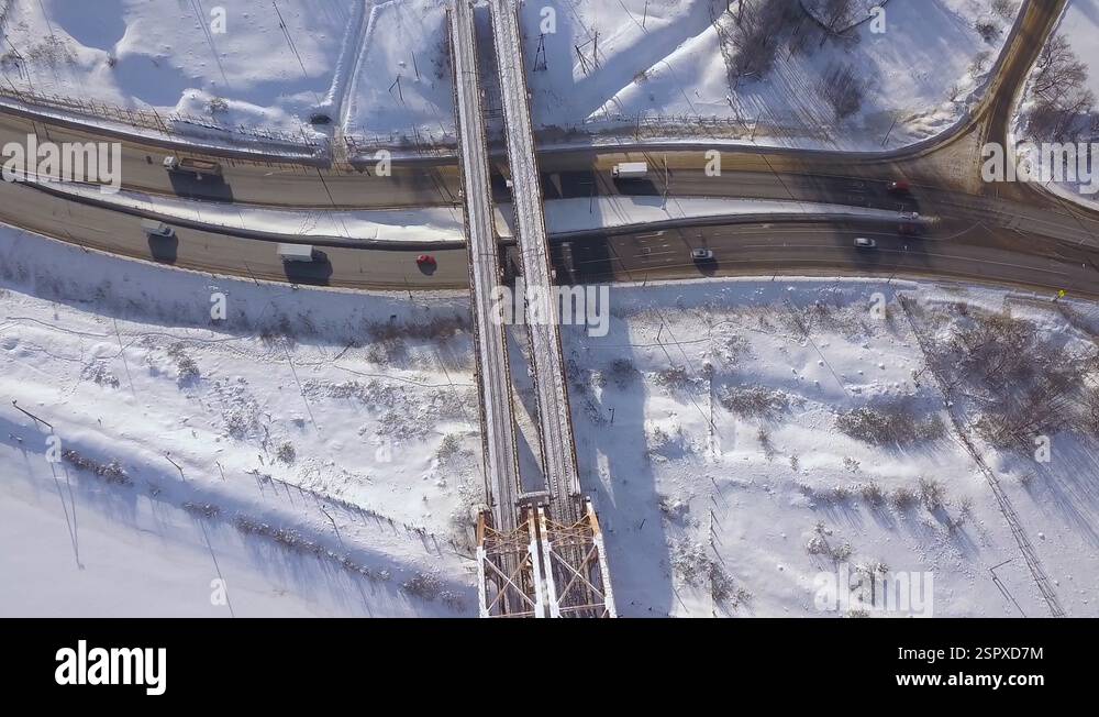 Cars and cargo trucks moving on winter highway under train bridge drone ...