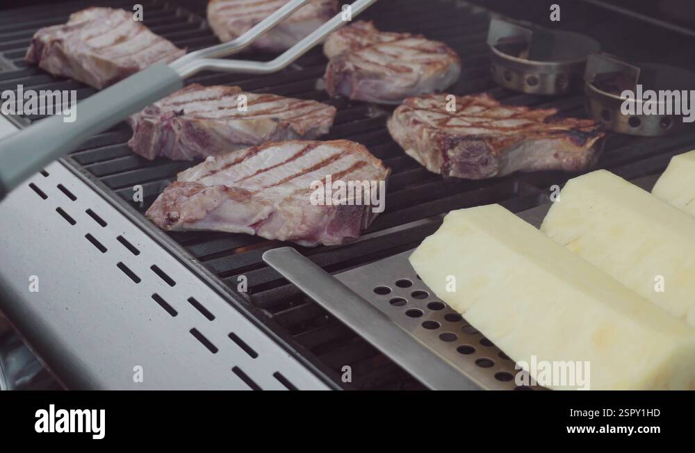 Cooking pork chops with pineapples on gas grill in the Summer Stock ...
