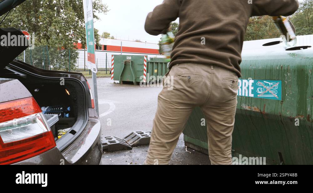 Man taking from car trunk glass waste bottles for recycling at facility ...