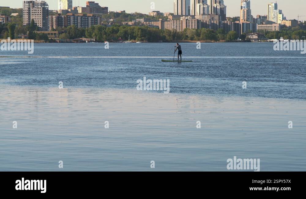 Very Long Shot, Young Guy Standing Sip on Sup on the River on the City ...