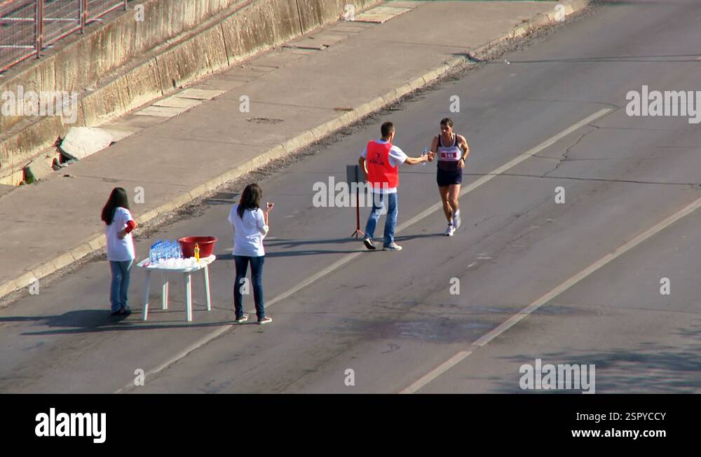 Marathon runner runing through the city and take water slow motion ...