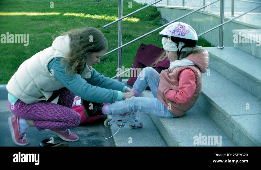 Mom and daughter ride on roller skates. Girl learning to roller skate ...