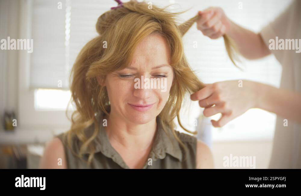 Hair stylist makes a curls for a girl, using hair styling. Hairdresser ...