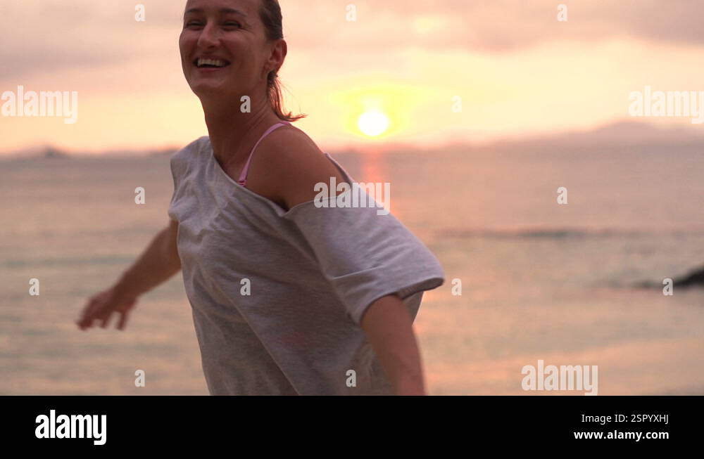 Happy, young woman with wide open arms enjoying sunset on beach, super ...