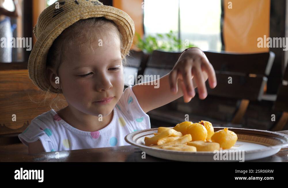 Little cute kid girl portrait sit in fast food restaurant eat chew ...