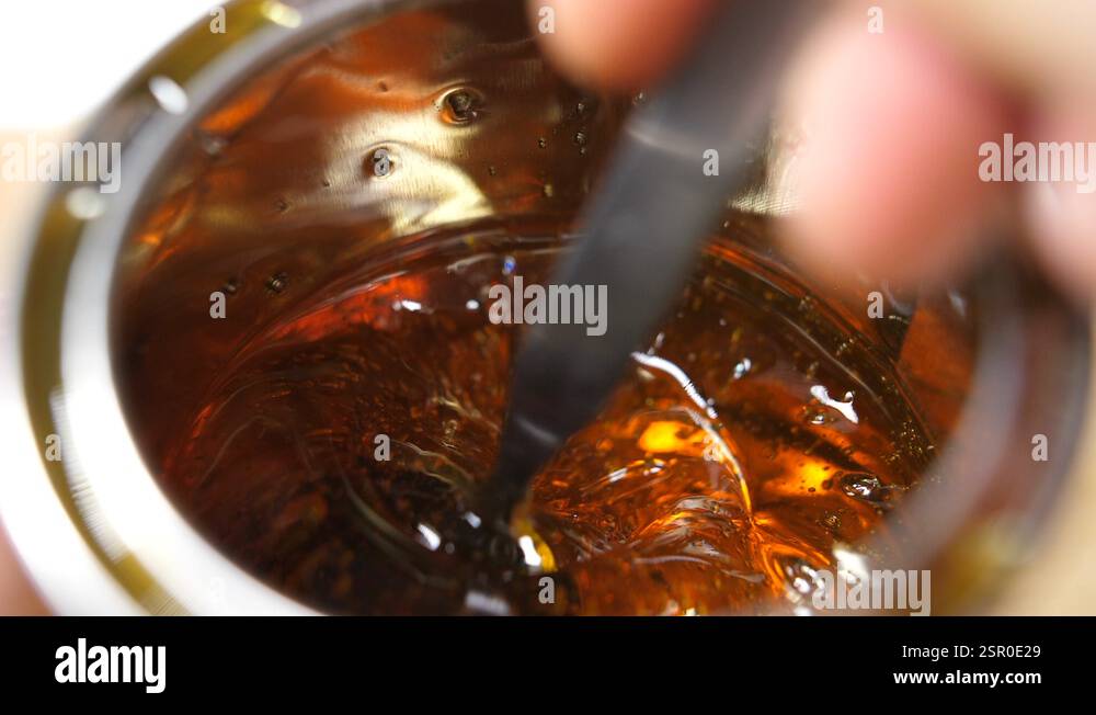 golden syrup pouring into a metal container, with a serving spoon ...
