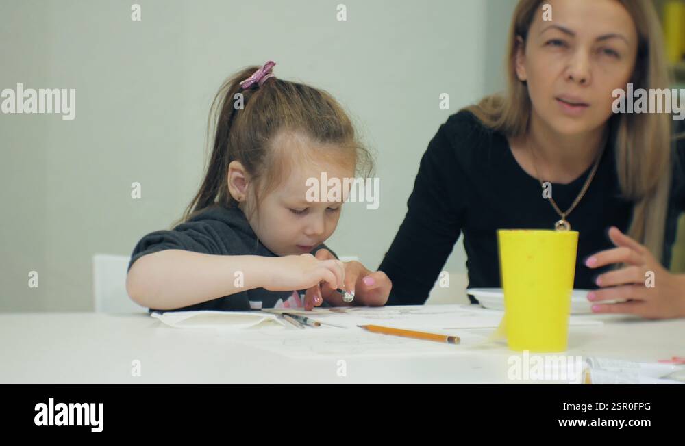 Children girls sit together at the table in the classroom and drawing ...