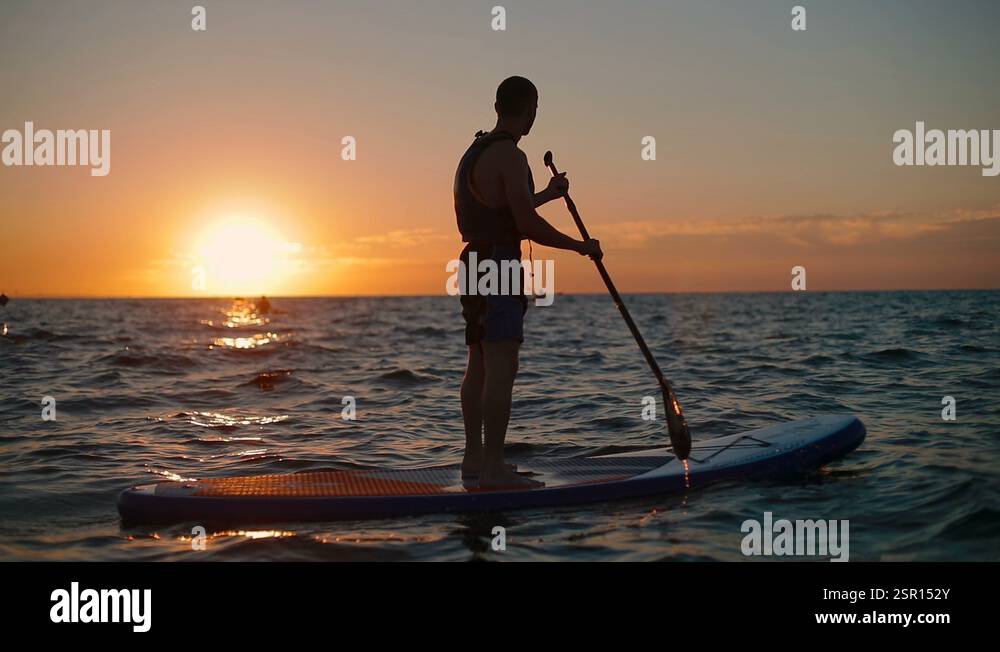 A man on a sap board meets the sunrise in the sea Stock Video Footage ...