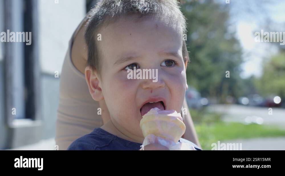 Toddler boy takes multiple quick licks of ice cream cone - close up on ...