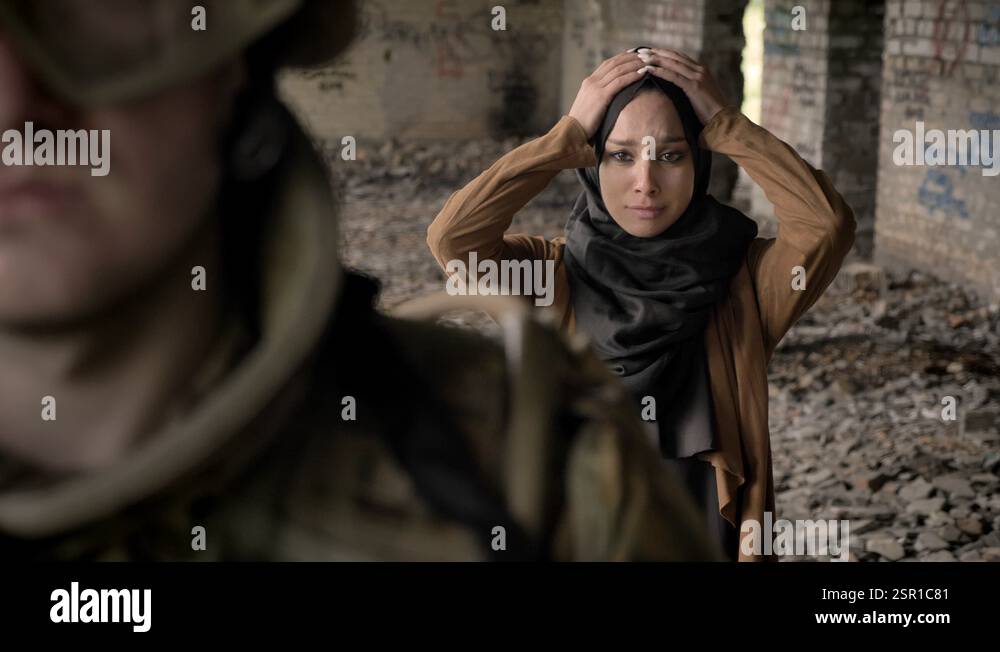 Young muslim woman in hijab screaming and crying behind armed soldier ...