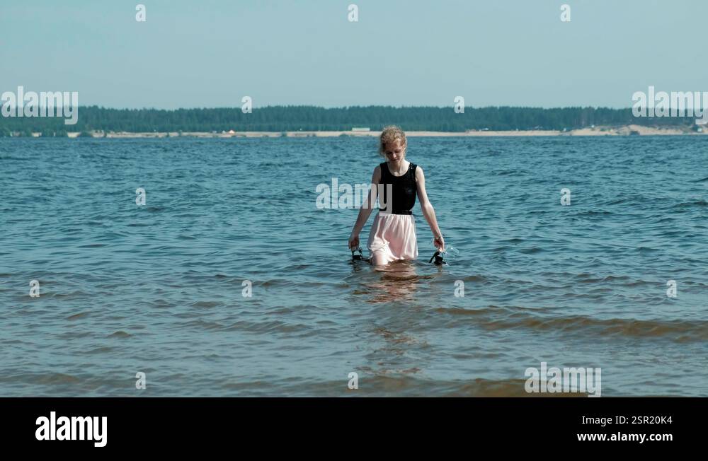 drunk woman walks into the water on the beach with a glass of wine ...