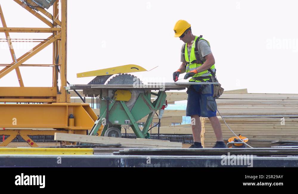 A workman works with wooden planks at a construction site - the bright ...