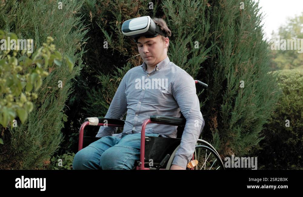 A disabled man in a wheelchair chair dresses a virtual reality helmet ...