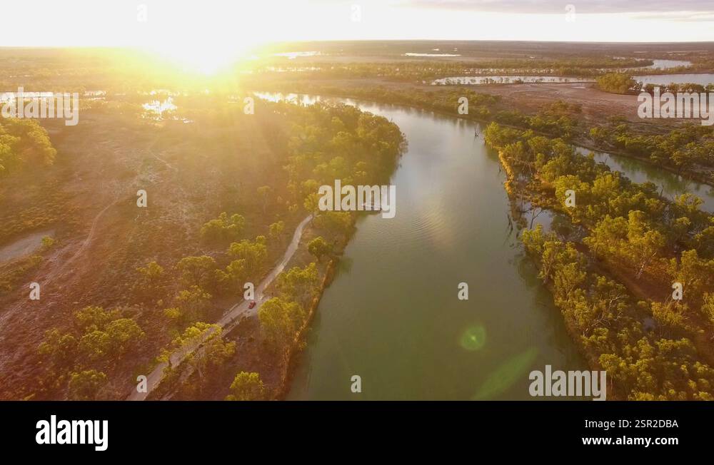 Slow aerial descend over Murray River at sunset with sun flare Stock ...