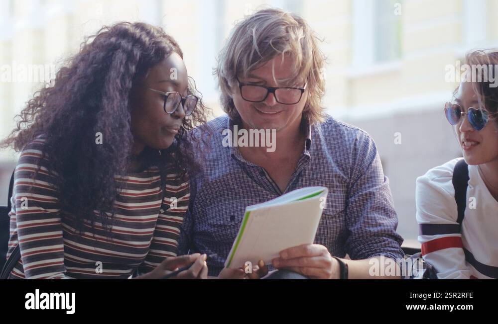 Professor explaining difficult task to students sitting on stairs Stock ...