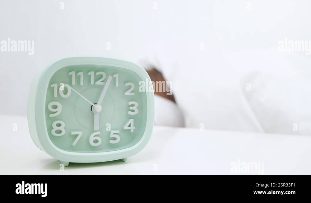 Wake up of an asleep girl stopping alarm clock on the bed in the ...