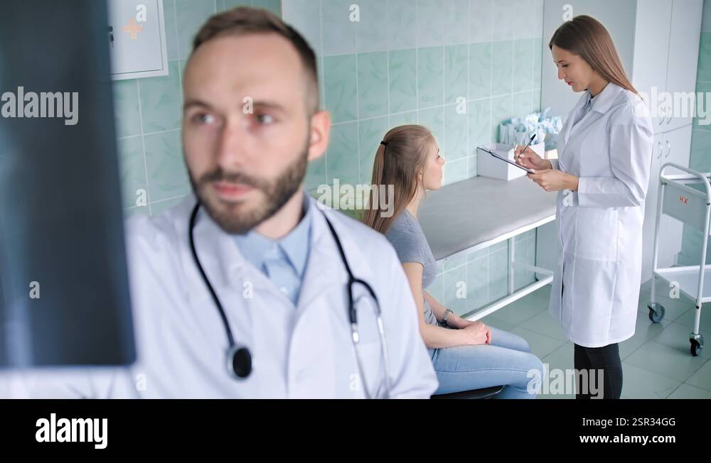Male doctor with stethoscope in white lab coat concentratedly reviewing ...