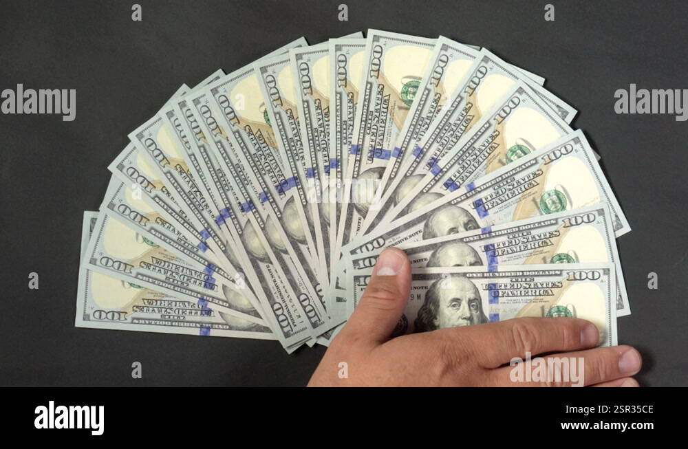 Money is spread out on the table with a fan. Dollars on a black ...