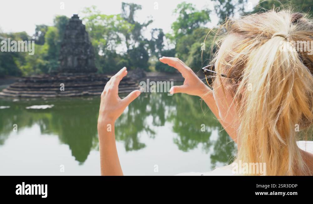 Young woman at water temple making heart shape finger frame with hands ...