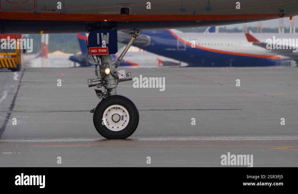 Landing gear of taxiing aircraft. Fore wheel of airplane moving on ...