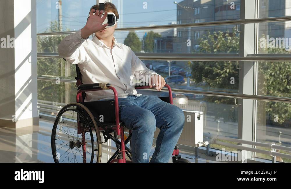 disabled man on a wheelchair at a window uses a helmet of virtual ...