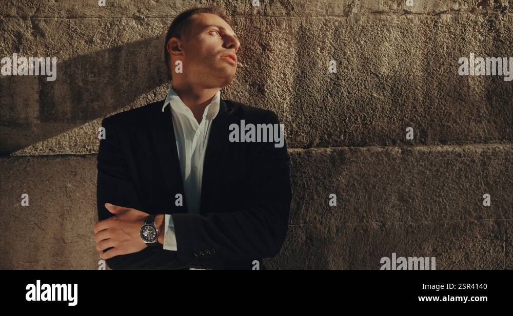 Handsome smiling man in a business suit checks time on his watch ...