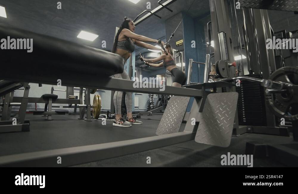 Girls doing exercise on back muscles in block simulator in slow motion ...