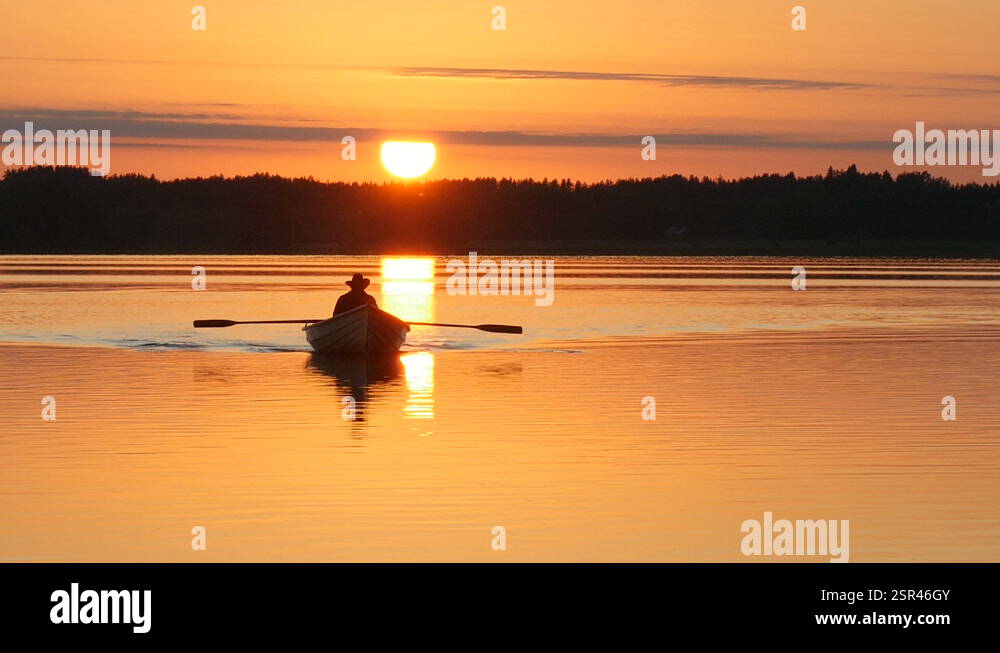 Beautiful solar path over lake and silhouette of man rowing on boat at ...