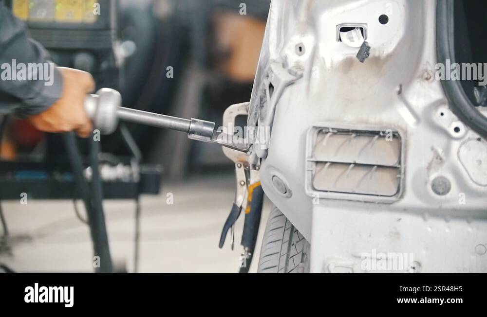 The mechanic's hands repair the car's part with a pulse soldering iron ...