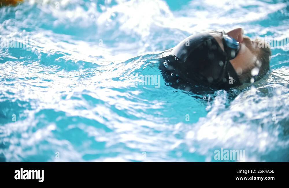 Disabled man swims on the back in a swimming pool. Slow motion. Side ...