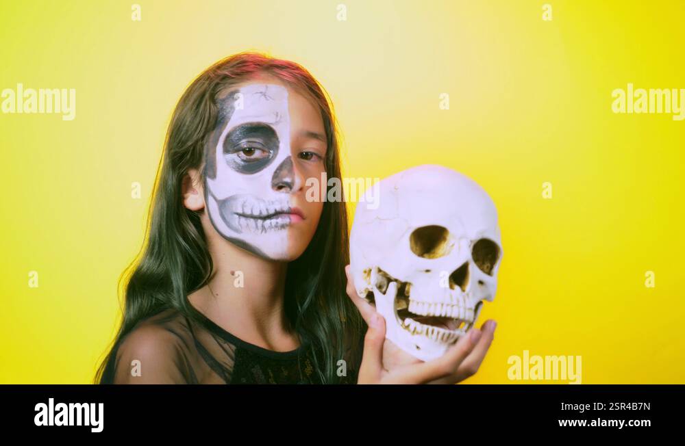 Halloween, girl with make-up skeleton on half face, dressed as witch ...