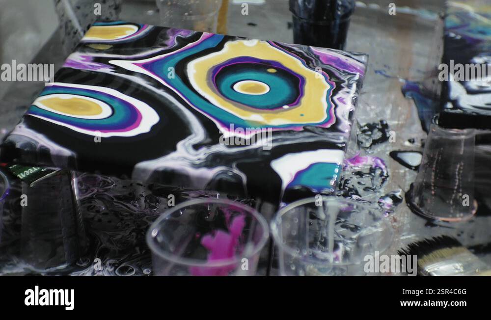 women in an art studio mix paints and draw on canvas in fluid art ...