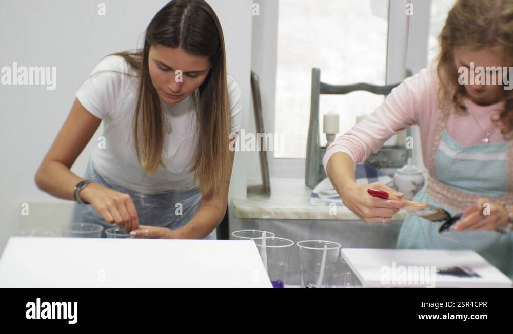 women in an art studio mix paints and draw on canvas in fluid art ...