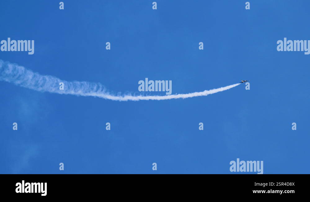 Dead loop. Airplane flying in blue sky and leaving a condensation trail ...