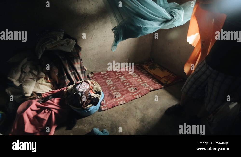 Inside a poor little house in Africa. A lot of clothes, linen lies on ...