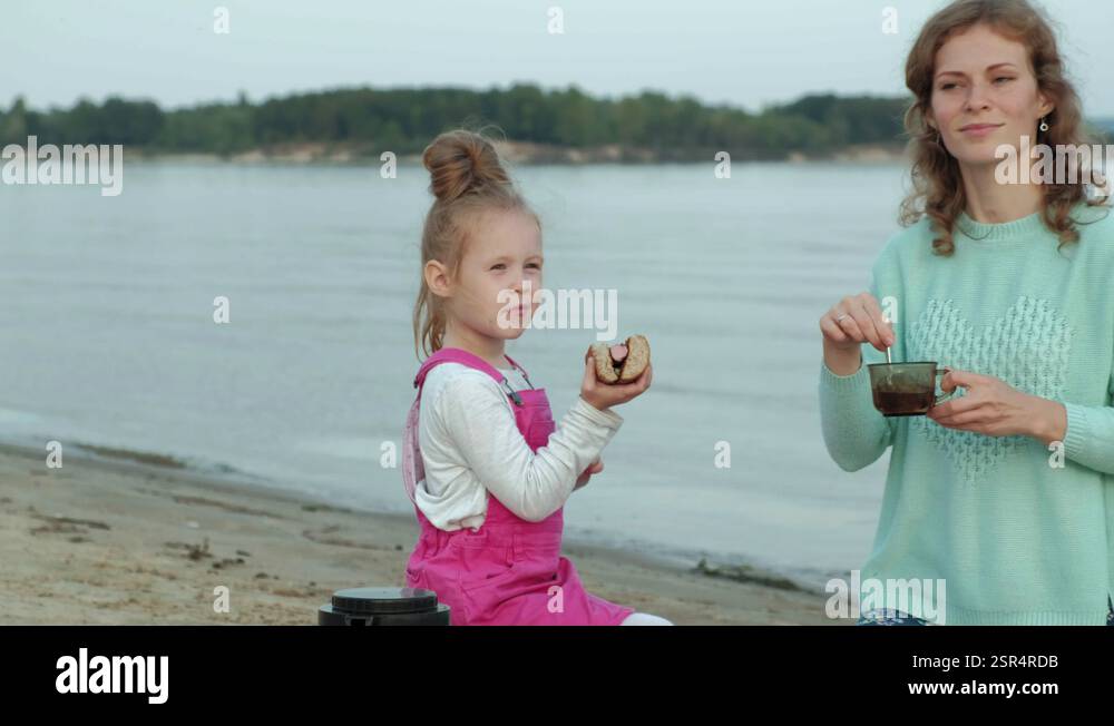 Mother and daughter fry meat and vegetables on a barbecue on the beach ...
