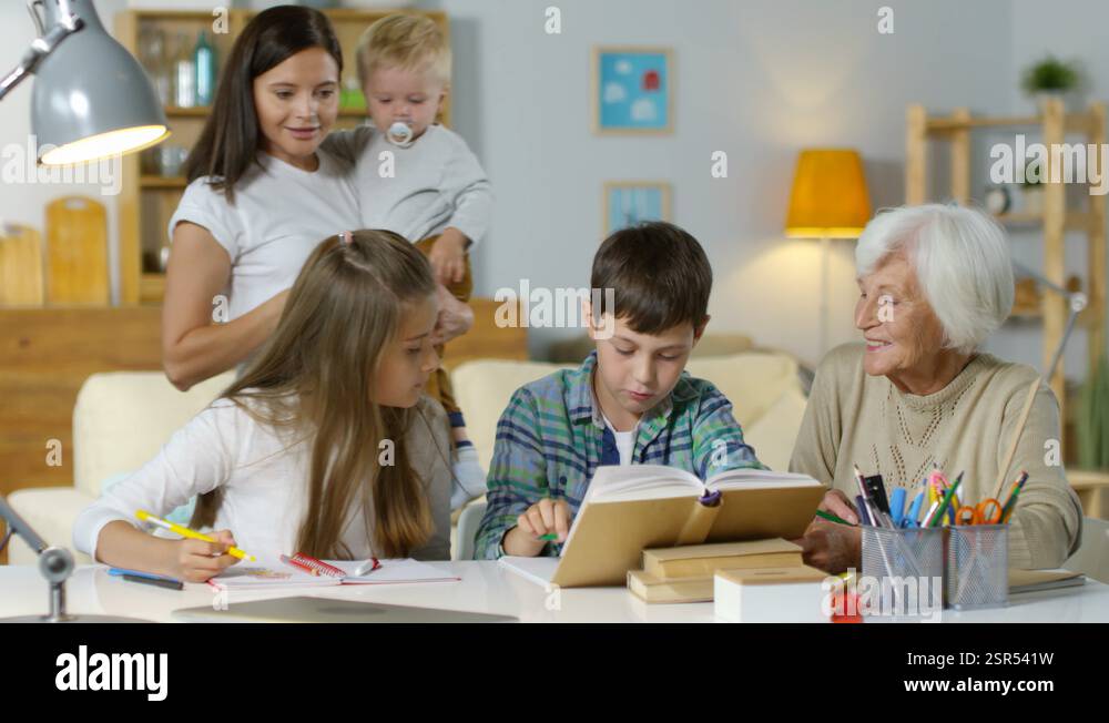 Kids Studying at Home with Grandma while Mother Coddling a Baby Stock ...