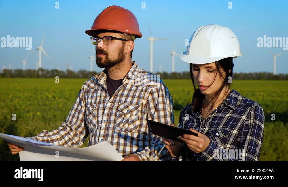 Two engineers discuss on plan on big piece of paper while walking in a ...