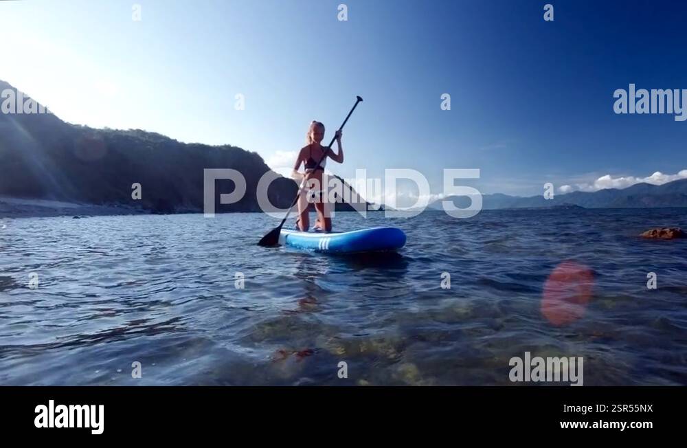 slim girl in bikini rows paddle board on open ocean Stock Video Footage ...