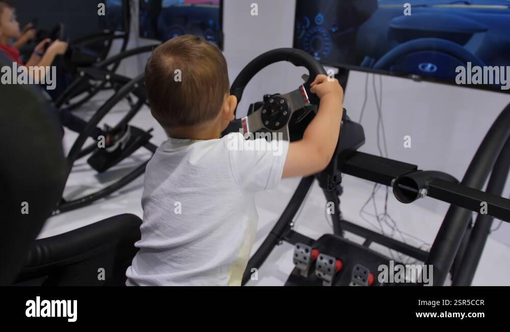 Baby boy plays in car driving simulator and turns a steering wheel ...