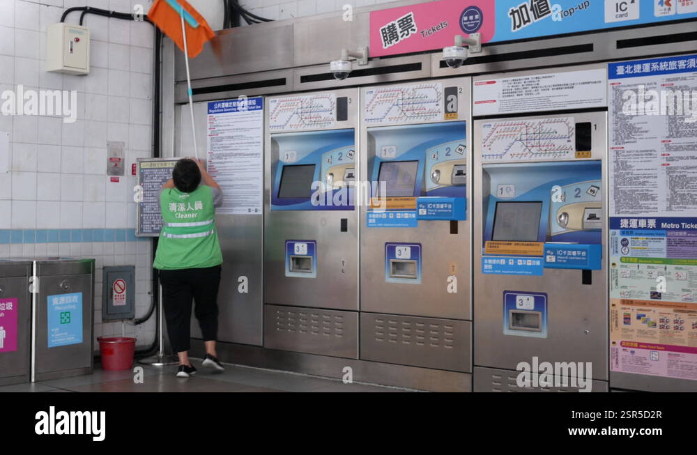 Motion of worker cleaning floor and wall near ticket machine inside MRT ...