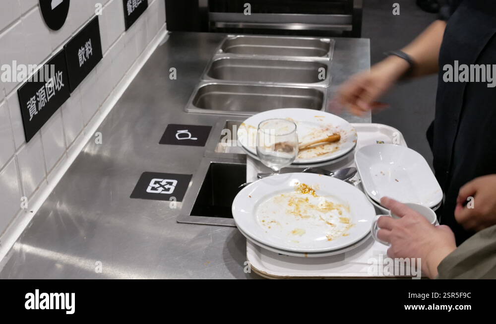 Motion of people cleaning leftover food at food court sorting station ...