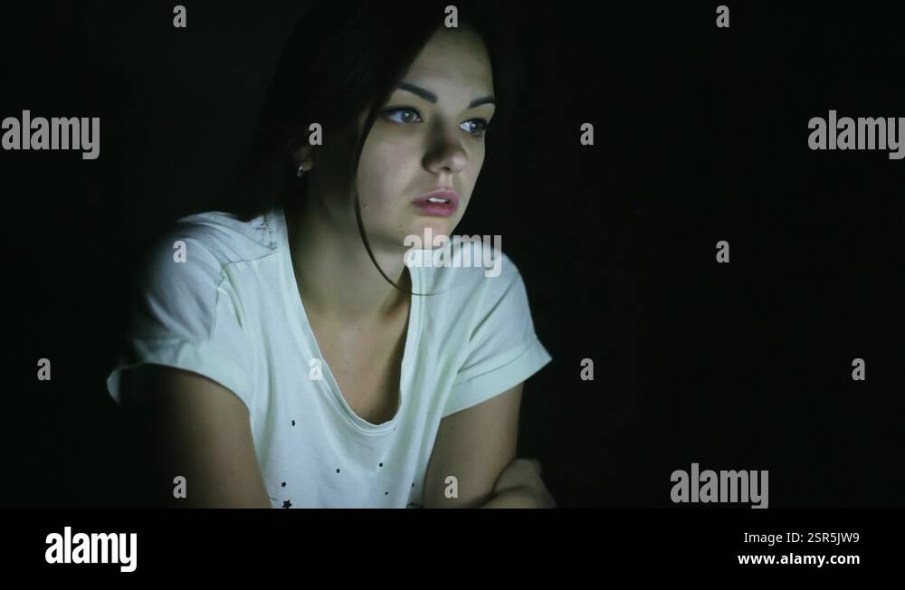 Woman watching horror movie alone on the notebook on the night. Very ...