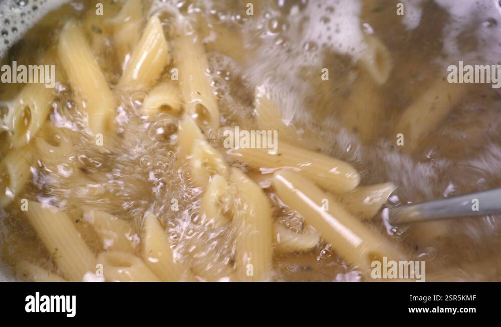 Boiling pasta in pan, mixing and checking with a spoon Stock Video ...