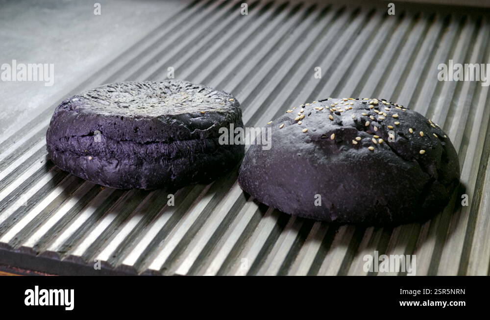 Black bun. Two halves of hamburger bread are being fried on grill for ...
