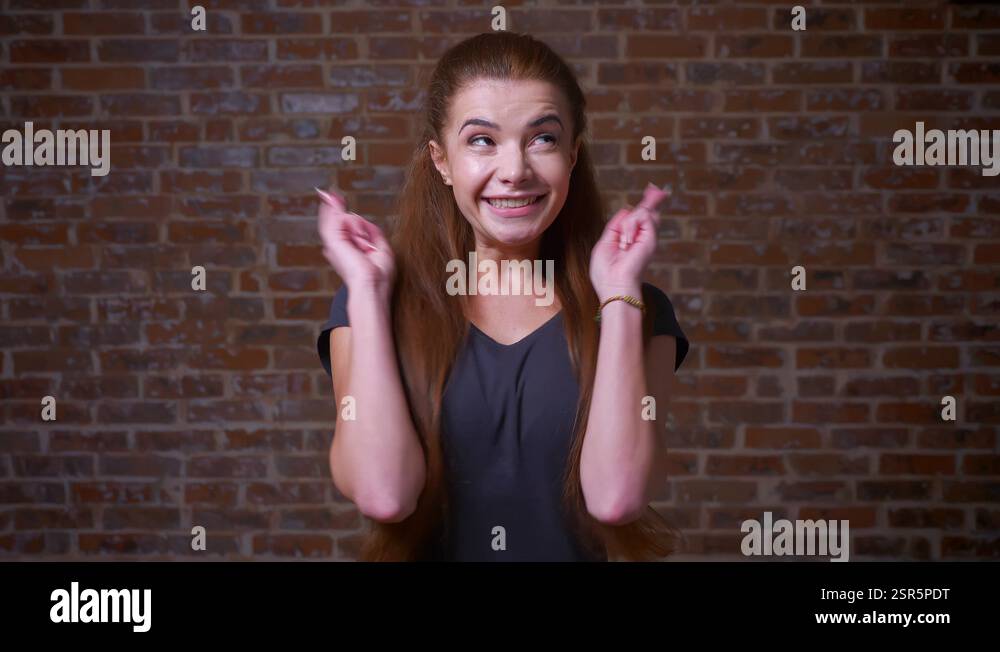 Artistic caucasian ginger female is wishing for luck with two fingers ...
