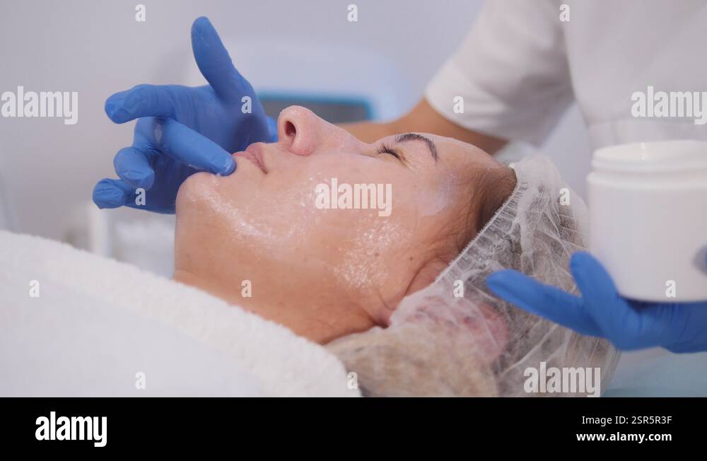 Cosmetology procedures. Peeling treatment. Smearing cream on the face ...